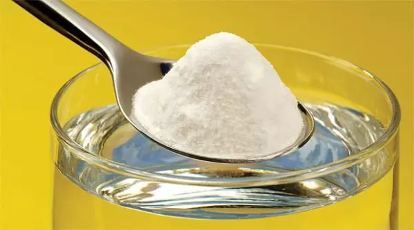 Cucchiaio con soda su un bicchiere con acqua