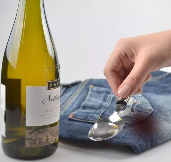 Bottiglia di vino bianco, jeans e cucchiaio con liquido