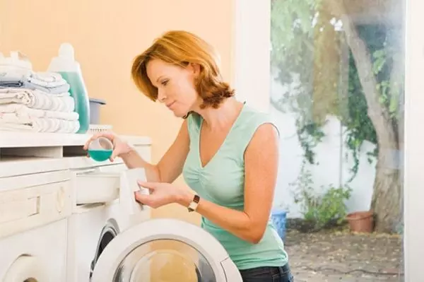 La donna carica la macchina da scrivere con la biancheria, si rivolge ai mezzi di lavaggio