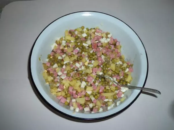 Rectificant els cogombres salats, els ous, el pernil, les patates bullides i els punts de polka en un bol gran