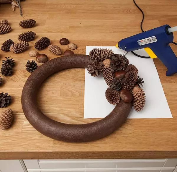 Blank for a festive wreath of natural materials and adhesive pistol on the table