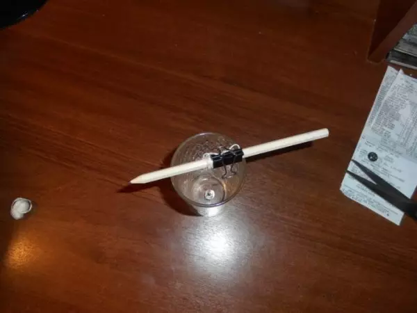 Fixing the wick of the homemade candle with a pencil and clamp