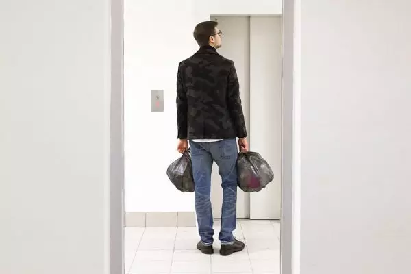 Een man staat bij de lift met afval