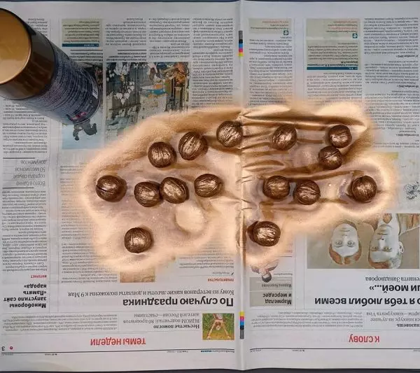 Painted golden spray paint walnuts on the newspaper