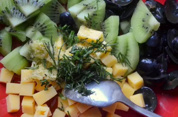 Paruošti ingredientai vaisių salotoms su sūriu ir metaliniu šaukštu