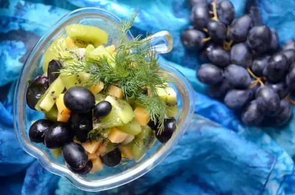 ສະຫຼັດຈາກ kiwi ແລະ grapes ກັບເນີຍແຂງແລະ dill ໃນໂຖປັດສະວະສະຫຼັດສ່ວນທີ່ສວຍງາມໃນຕາຕະລາງທີ່ມີ graces ໄດ້