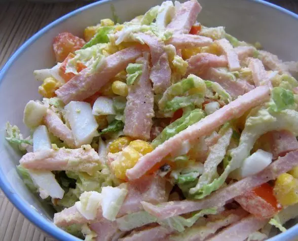Snack salad with ham and canned corn in the ceramic container of a small volume