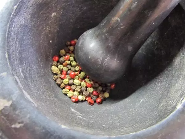 Grinding a mixture of peppers into a mortar