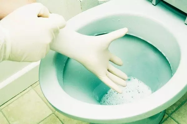 Ręka w rękawicy i niebieska toaleta