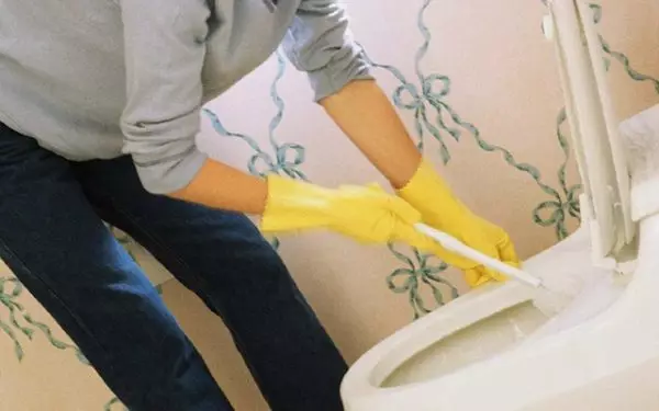 پیلے رنگ کے دستانے میں ہاتھ ٹوائلٹ صاف کریں