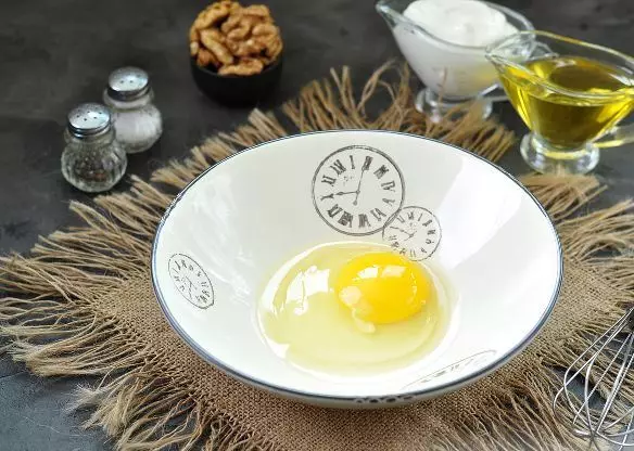 O conteúdo do ovo de frango cru em uma placa profunda na mesa
