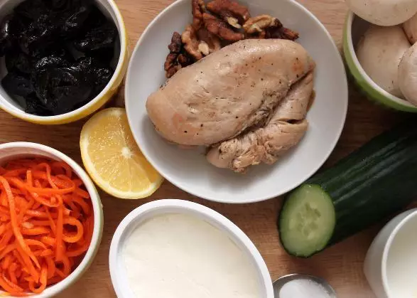 Produkter til matlaging Salat med svisker, kylling og koreanske gulrøtter på bordet