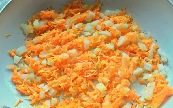 Curly carrot and chopped onions in a frying pan with non-stick coating