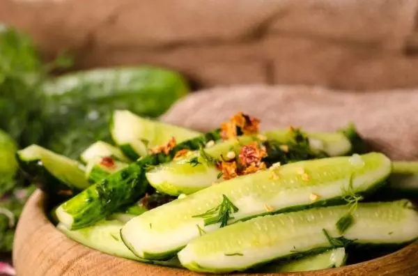 Cucumbers lightweight le Greens agus piobar géar in umar adhmaid ar an tábla