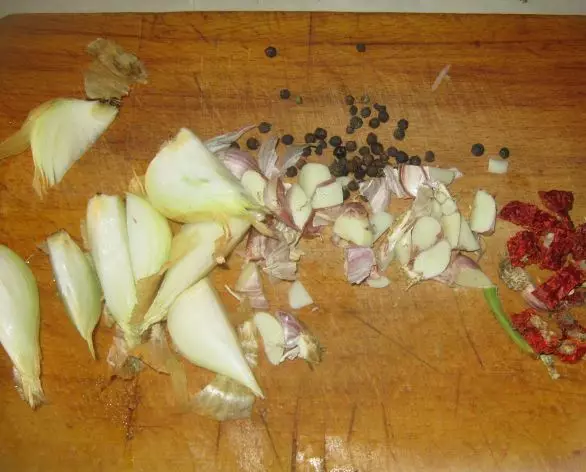 木製のまな板の上の玉ねぎ、ニンニク、乾燥黒唐辛子とコショウピーマン