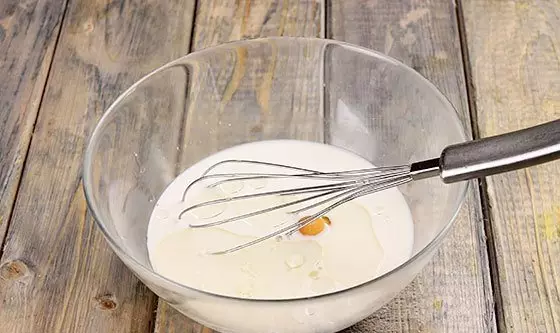 Whisk kim loại, sữa và trứng trong một bát thủy tinh