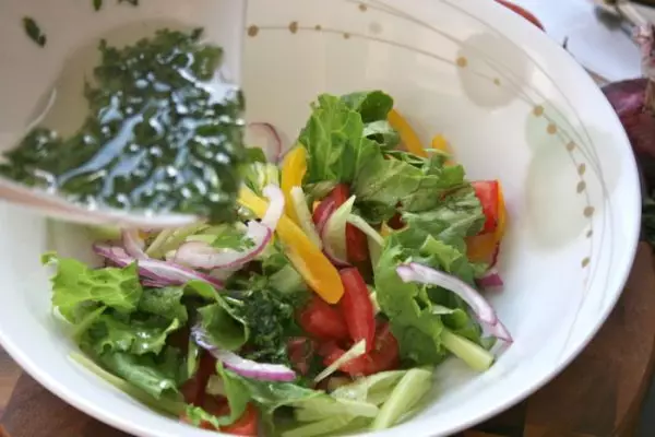 Dolivanje biljne salate sa mješavinom ulja, limunovog soka i zelenila