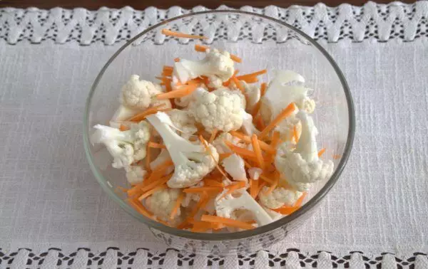 Irisan kembang kol mentah dengan wortel dan bawang putih dalam mangkuk kaca dalam