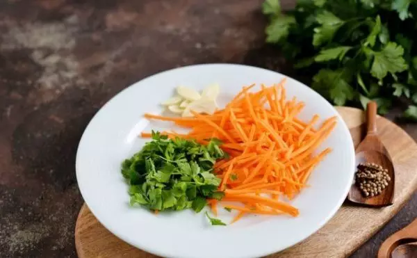 Gehackte frische Grüns, geriebene Karotten und gehackter Knoblauch auf einem weißen Teller