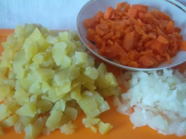 Dihiris dengan kiub kecil kentang rebus, wortel dan bawang di permukaan kerja