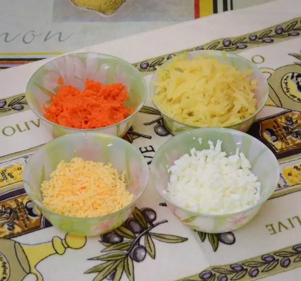 Proteínas hervidas rizadas y yemas, papas y zanahorias en diferentes capacidades sobre la mesa.