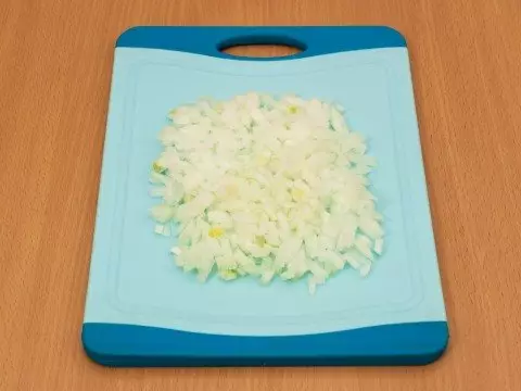 Smulkiai supjaustyti svogūnai ant mėlynos pjaustymo plokštės