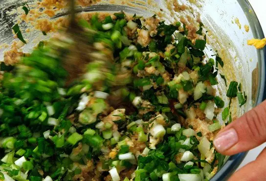 Sekoittaminen salaattia turskan maksasta ja vihreästä sipulista lasisäiliöissä