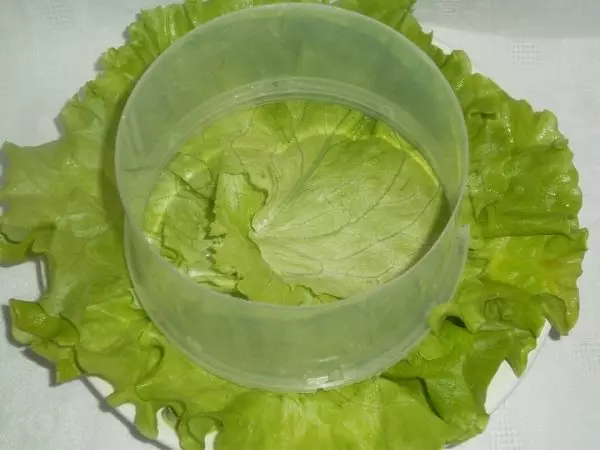 Anello di stampaggio in plastica su un piatto con foglie di insalata