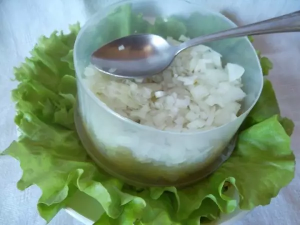 धातूच्या चमच्याने प्लास्टिकच्या रिंगमध्ये सॅलड तयार करणे