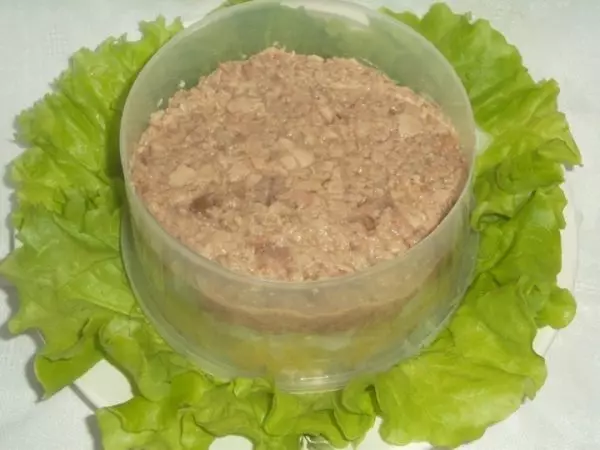 Hígado de bacalao de molienda en el anillo de moldeo de plástico en la placa con hojas de ensalada