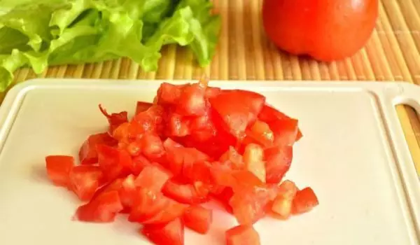 Bitar av mogen tomat på ett skärbräda