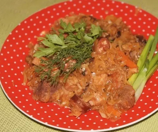 সবুজ শাকসবজি সঙ্গে লাল প্লেট উপর পোলিশ bigos