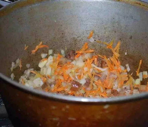 Lilọ alubosa pẹlu awọn Karooti grated ninu Kazan