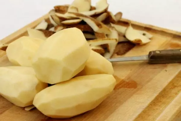 תפוחי אדמה מטוהרים על לוח חיתוך