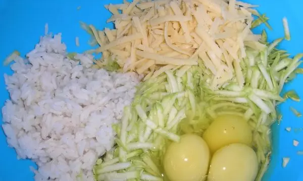 Boiled rice, grated zucchini, cheese and eggs in a bowl