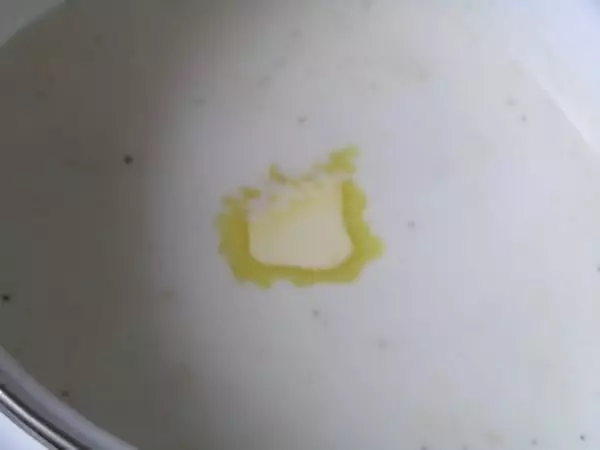 Una rebanada de mantequilla en una cacerola con sopa de leche.