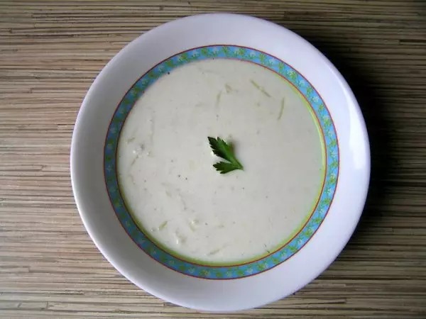 Mléčná polévka s vermicellus, kuřecí a čerstvé petrželky v talíři na dřevěném povrchu