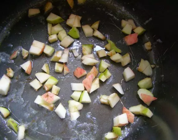 Irisan epal dalam mangkuk multicooker dengan mentega