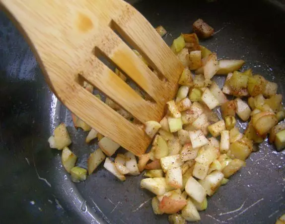 Morceaux de rôtis avec des épices de pommes dans un bol de multicolteurs et une lame en bois