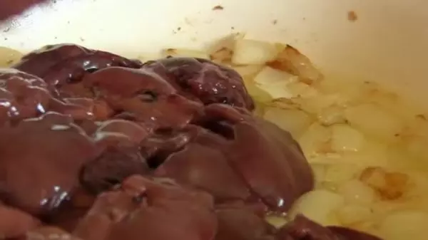 Hígado de pollo crudo y cebollas asadas en una sartén con aceite vegetal