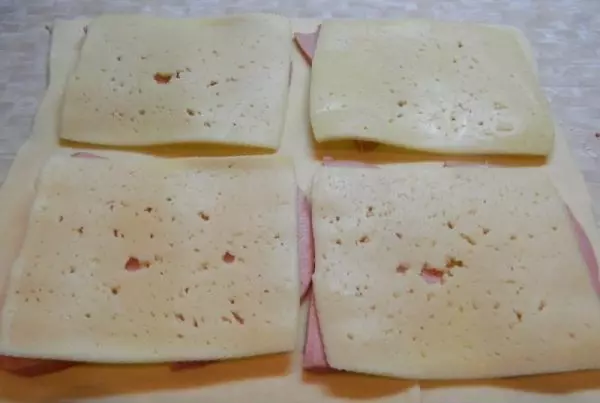 Сум тесто слој со колбаси и цврсти сирење парчиња