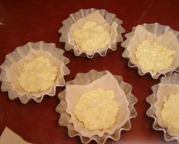 بخش های فلزی برای کلوچه ها با تکه های خمیر خام و پنیر خامه ای شکل می گیرد