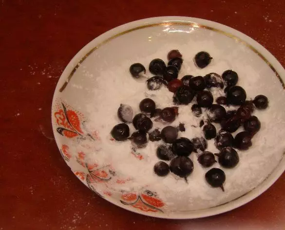 Crne ribizle bobice u tanjuru sa škrobom na stolu