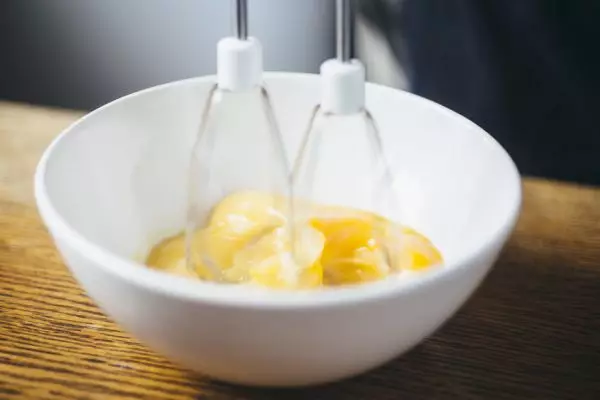 Huevos en un tazón y mezclador blancos.