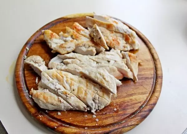 Нарязани ленти печено пилешко филе на дъска за рязане