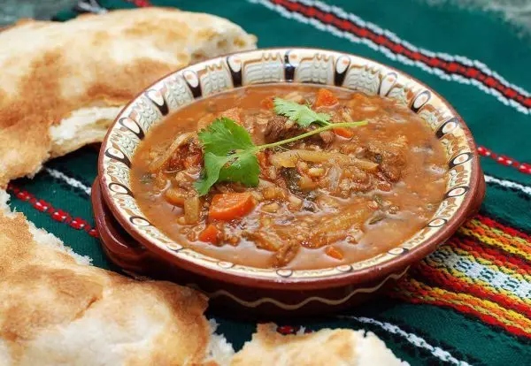 Грузинський суп харчо в тарілці на столі з лавашем