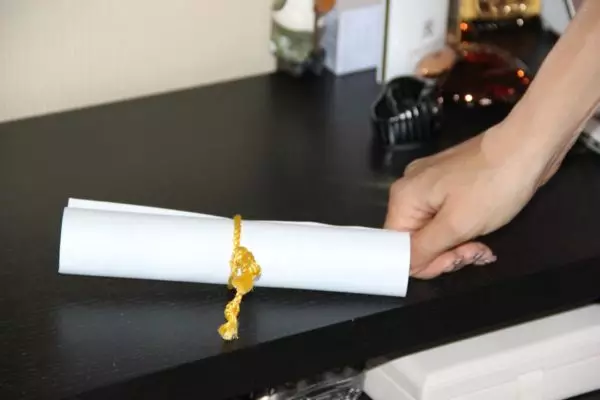 Mão feminina perto da folha de papel esculpida amarrada com corda amarela