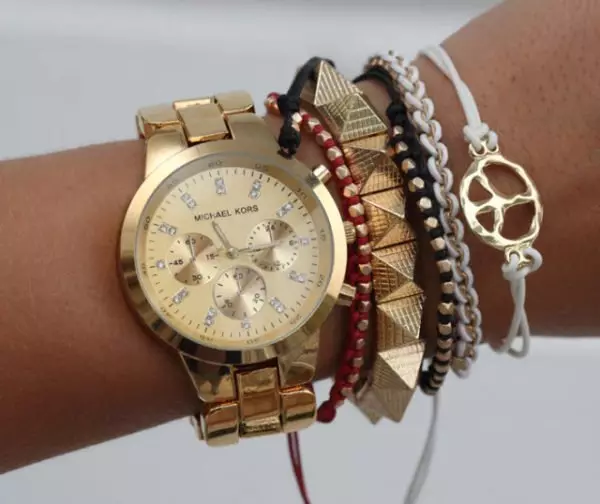 Wrist with bracelets and clock on a light bracelet