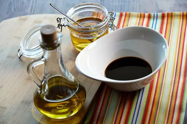 Olivenolie, flydende honning og balsamicoeddike på bordet