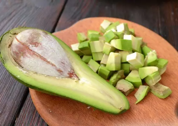 Theka avocado ndi zidutswa za zipatso pamatabwa odula mitengo